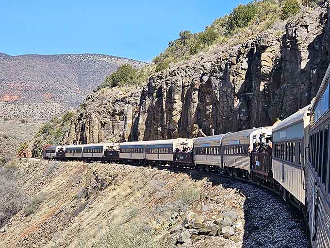 The train snakes along dramatic cliff faces, carrying passengers through wilderness accessible only by these historic rails.