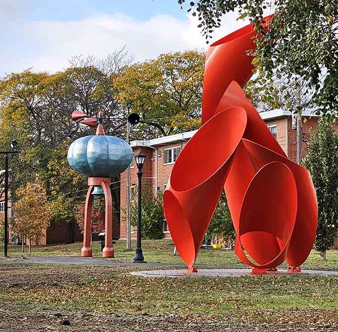 Bold red abstract forms rise dramatically beside quirky companions, creating a conversation between contrasting artistic voices.