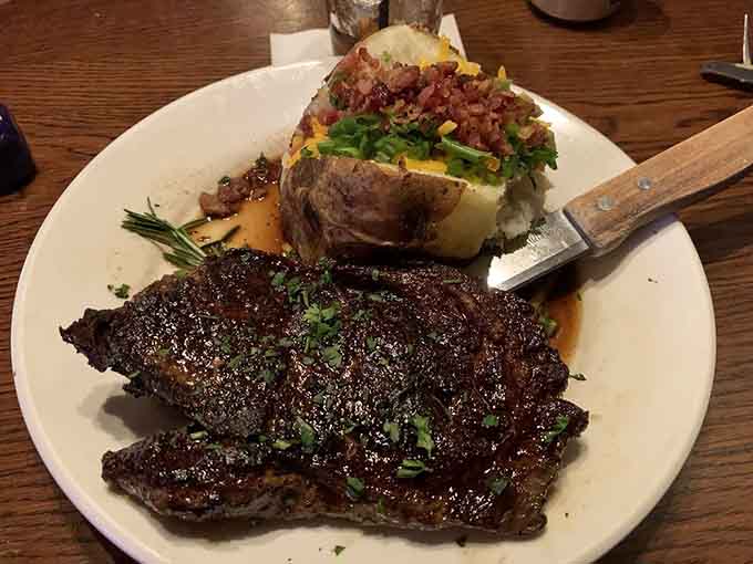 A ribeye so perfectly charred it deserves its own standing ovation, loaded potato included for dramatic effect.