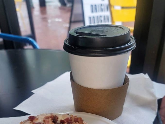 That cardboard sleeve means serious business is happening inside, fueling doughnut decisions one perfectly brewed sip at a time.