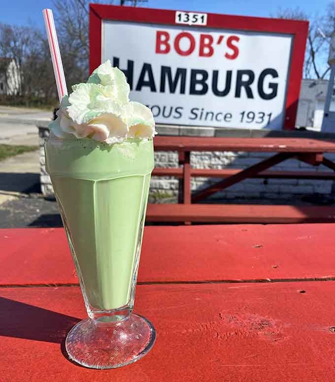 A mint green milkshake topped with whipped cream, looking like something from a 1950s soda fountain fever dream.