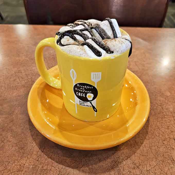 Hot chocolate topped with whipped cream and chocolate drizzle in a cheerful yellow mug, because adults deserve treats too.