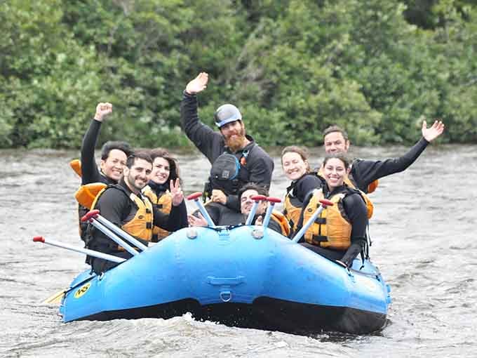 Happy rafters celebrate conquering rapids together, their smiles bigger than the waves they just rode through successfully.