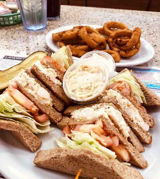 This triple-decker club sandwich towers like a skyscraper of flavor, accompanied by golden onion rings for maximum satisfaction.