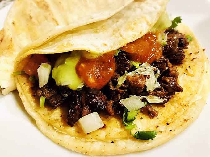 Simple perfection on a plate: fajita beef topped with vibrant salsa, diced onions, and cilantro on a warm tortilla.