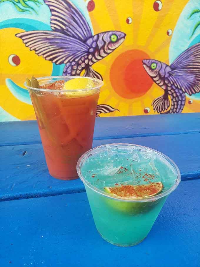 Bright cocktails against vibrant fish art, because even your beverages deserve to feel like they're on a tropical vacation.