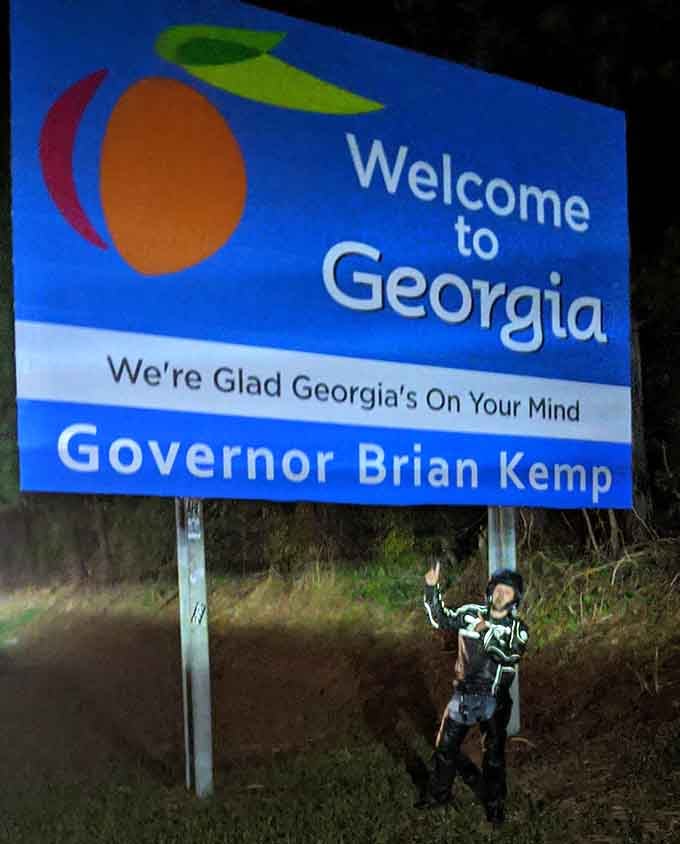 Nighttime doesn't stop determined travelers from celebrating their arrival with a triumphant pose beside the illuminated welcome.
