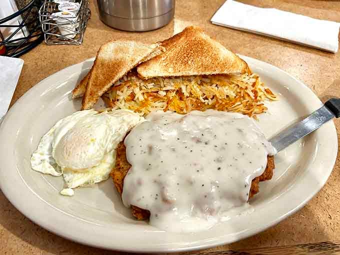 Country fried steak blanketed in white gravy, served with hash browns and toast, because sometimes breakfast needs to be taken seriously.