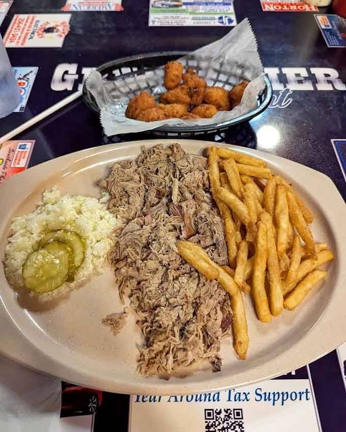 Pulled pork piled high enough to require architectural support, flanked by fries that know their supporting role matters too.