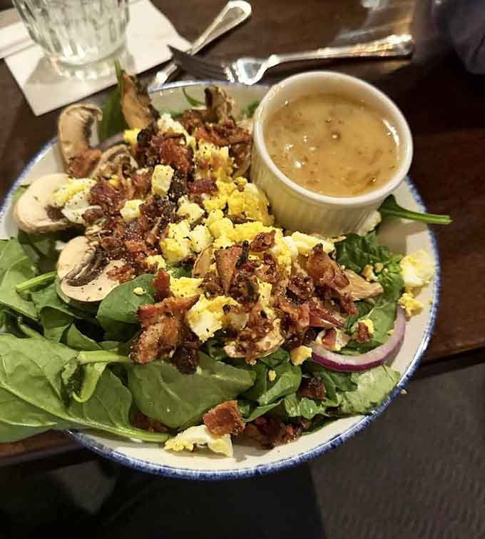 A spinach salad loaded with bacon and egg proves even the lighter options come with serious flavor commitment.