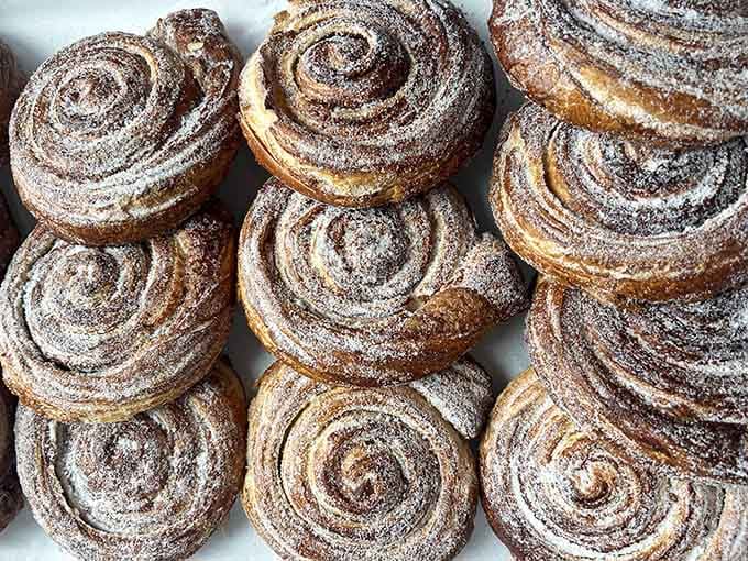 Cinnamon rolls dusted with powdered sugar like they just came back from a very sweet snowstorm.