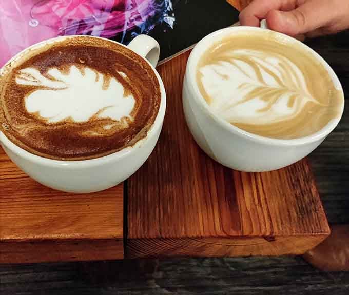 Two lattes with gorgeous foam art sitting on rustic wood, because sometimes presentation matters as much as taste does.