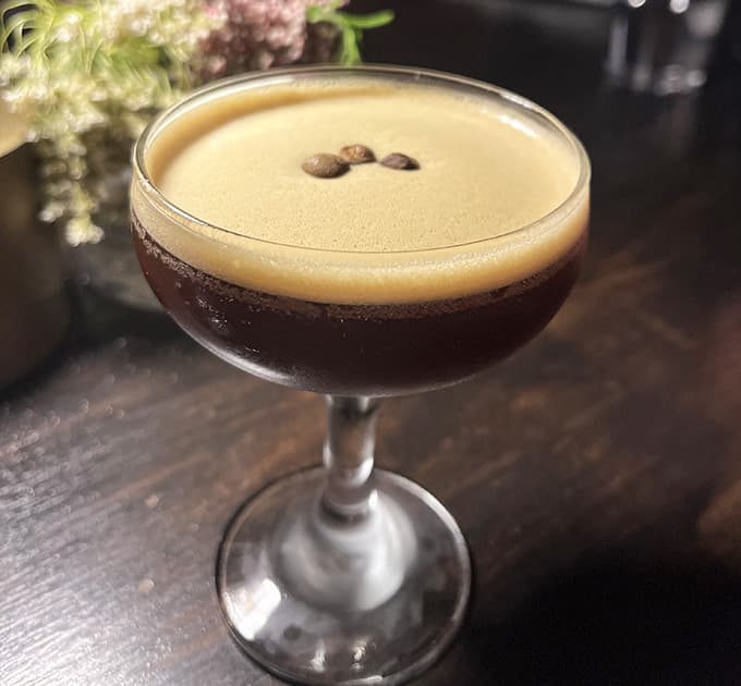 Three coffee beans float atop this velvety espresso martini like tiny life rafts of caffeinated joy.