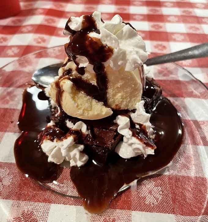 This towering brownie sundae with whipped cream and chocolate sauce is basically happiness served on a checkered tablecloth.