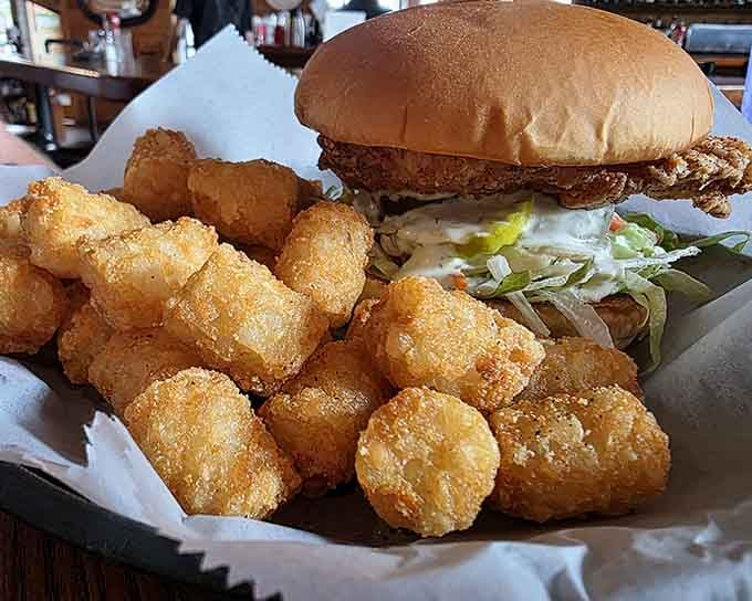 Tater tots piled high next to a crispy chicken sandwich create the kind of plate that makes dieting seem silly.