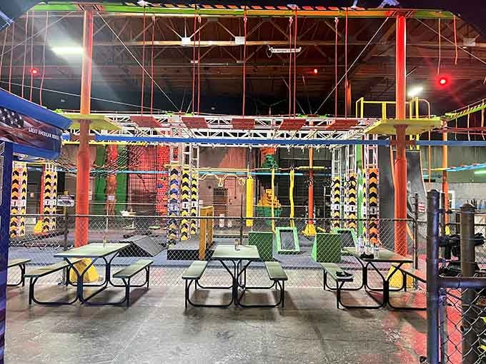 Picnic tables sit beneath the towering obstacle course, offering front-row seats to watch daring young adventurers conquer challenges.