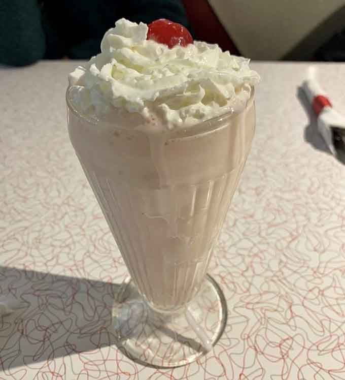That towering strawberry milkshake crowned with whipped cream and a cherry screams classic American indulgence at its finest.