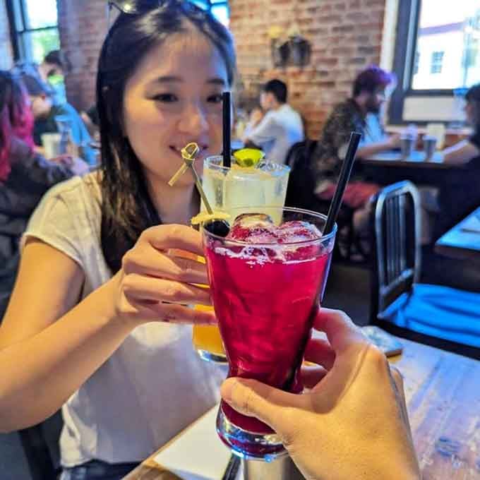 Colorful cocktails clinking together because even casual spots deserve a proper toast to good food and company.