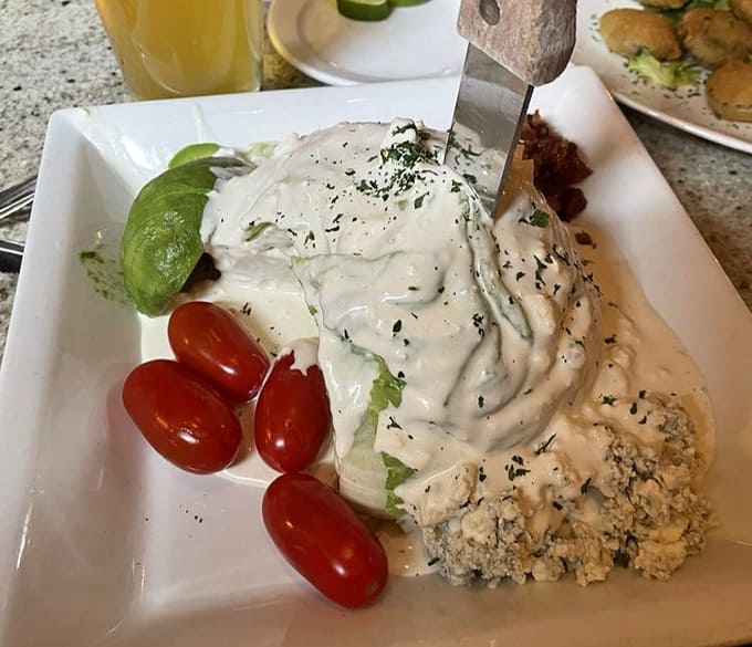 This wedge salad arrives dressed to impress, with creamy dressing cascading over crisp iceberg like a delicious avalanche.