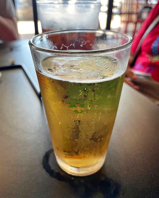 A cold beer catching the light, because great pizza deserves equally great liquid accompaniment for the journey.