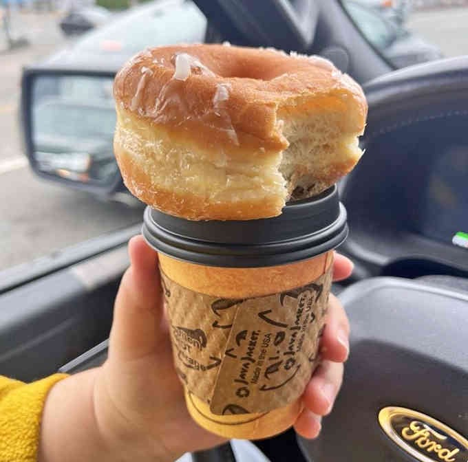 The perfect pairing: hot coffee and a glazed donut perched on top like a delicious edible lid.