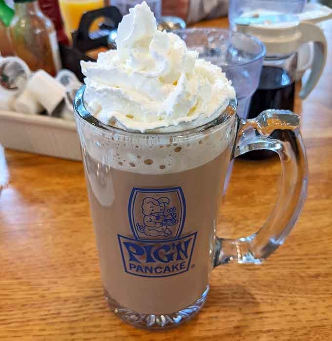 Hot chocolate topped with whipped cream in a branded mug proves that some pleasures are simple, sweet, and absolutely worth the calories.