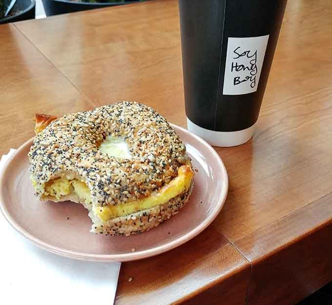 An everything bagel with egg and a coffee that says "Soy Honey Boy" because even your beverage deserves a personality.