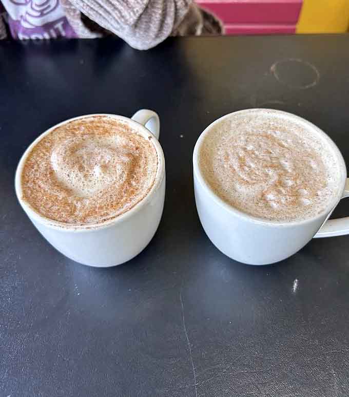 Two chai lattes topped with cinnamon swirls that look almost too pretty to drink—almost being the operative word here.