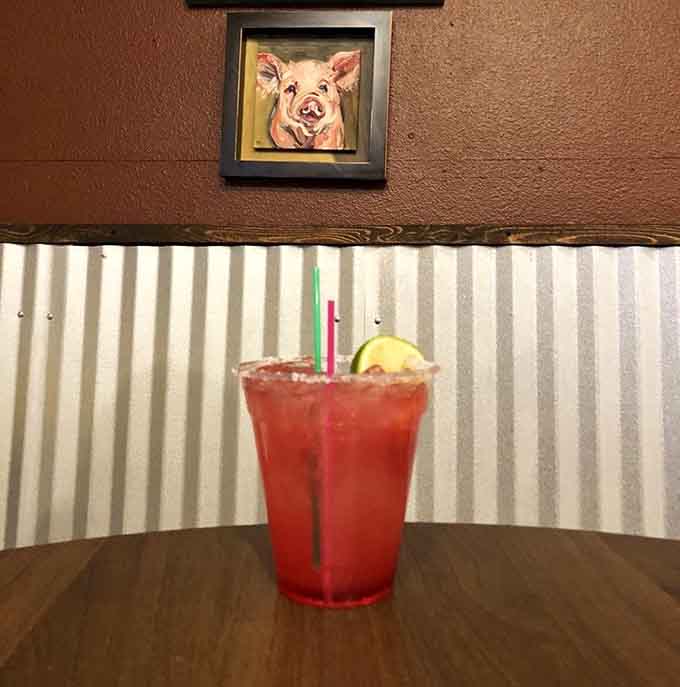 A refreshing beverage beneath a cheerful pig portrait, because even swine appreciate good hydration after all that delicious smoking business.