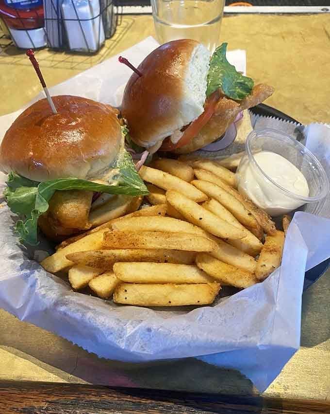 These sliders on pretzel buns with a mountain of fries represent lunch done right, no fancy presentation required for satisfaction.