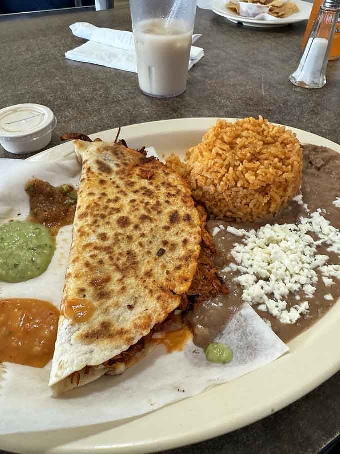 A properly grilled quesadilla with that ideal cheese pull, served with rice, beans, and all the traditional accompaniments.