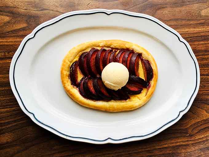 Rustic plum galette topped with ice cream proves that even seafood restaurants can nail dessert when they put their minds to it.