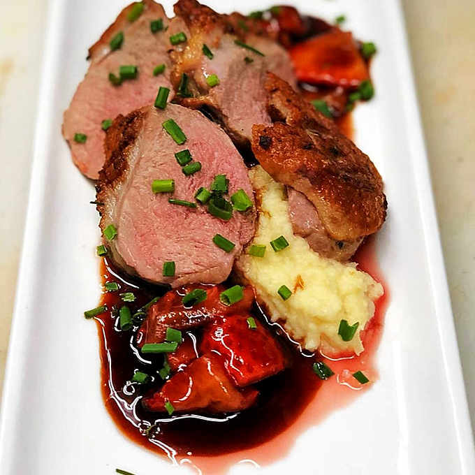 Duck breast sliced to reveal that perfect pink center, plated with the kind of precision colonial cooks never imagined.