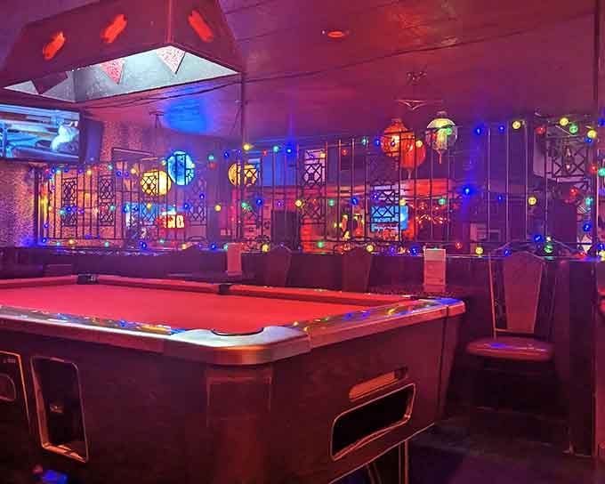 The pool table sits ready for action beneath colorful vintage lighting that would make any 1960s rec room jealous.