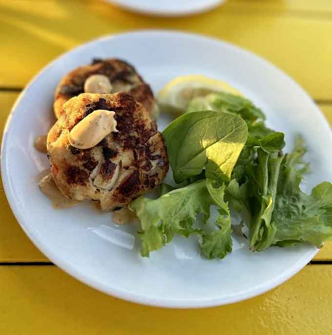 Crab cakes golden and gorgeous, sitting pretty on fresh greens like they just won a beauty pageant.