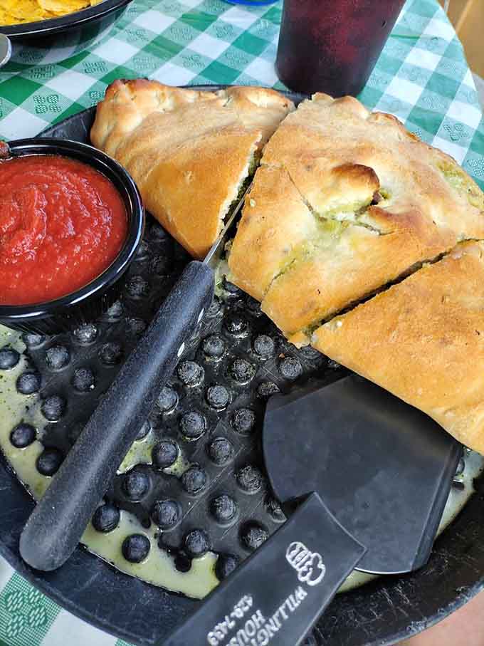 Golden-brown calzone perfection served with marinara sauce for dipping makes choosing between pizza and calzone genuinely difficult.