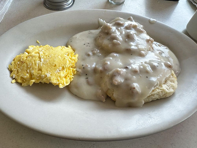 Biscuits and gravy that could anchor a ship, served alongside scrambled eggs for maximum morning satisfaction.