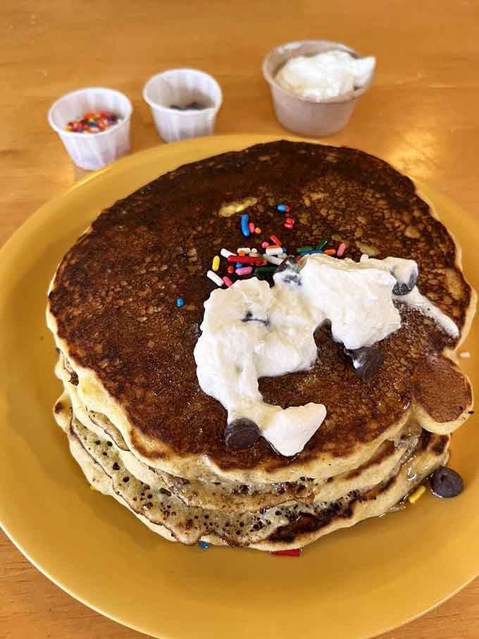 Johnny Cakes stacked high with whipped cream and sprinkles, because sometimes breakfast should feel like a celebration.