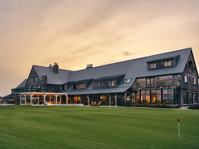 Golden hour bathes this Scottish-style clubhouse in warm light, making the manicured greens glow like emerald velvet carpeting.