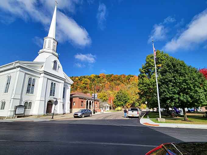 That white church steeple and tree-lined village square capture the essence of classic New England charm meets European simplicity.