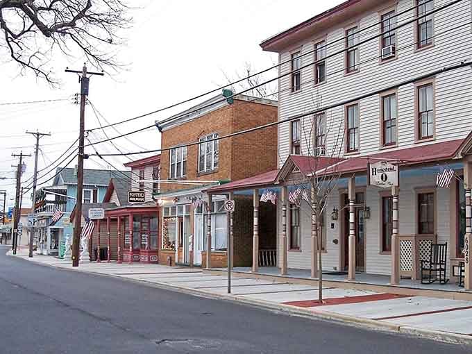 Warm-hued storefronts and American flags create a welcoming main street scene that feels authentically small-town without being sleepy.
