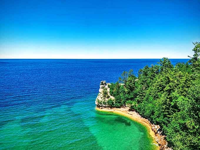 Brilliant blue water meets emerald green shallows around a dramatic rock formation jutting from Superior's pristine shore.