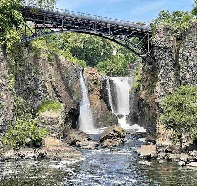 The historic bridge arches gracefully over Passaic Falls, framing the rushing water in a perfect marriage of engineering and nature.