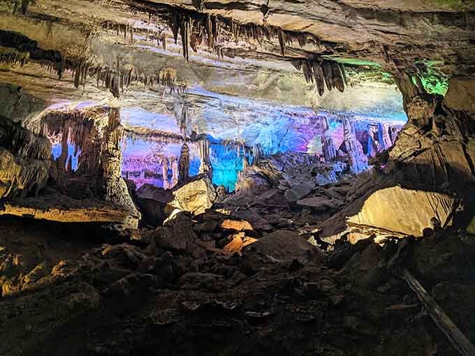 Underground chambers glow in electric blues and purples, revealing stalactites hanging like frozen chandeliers from the ancient ceiling.