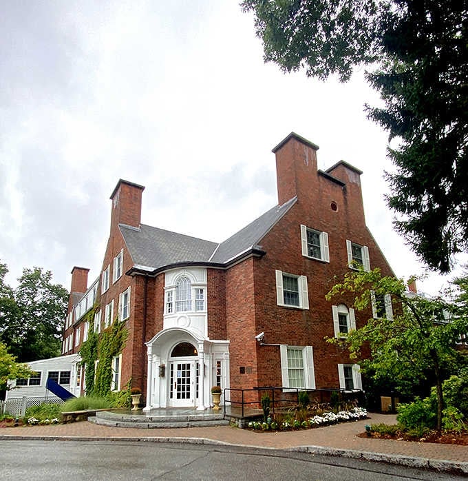 The classic brick architecture and white entrance columns suggest refined elegance and traditional New England hospitality.
