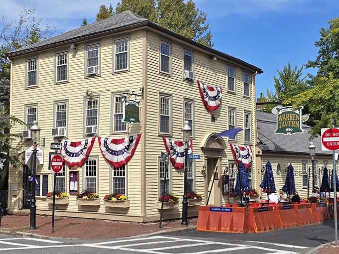 Patriotic bunting decorates this butter-yellow colonial building where revolutionaries once gathered and history still echoes through doorways.
