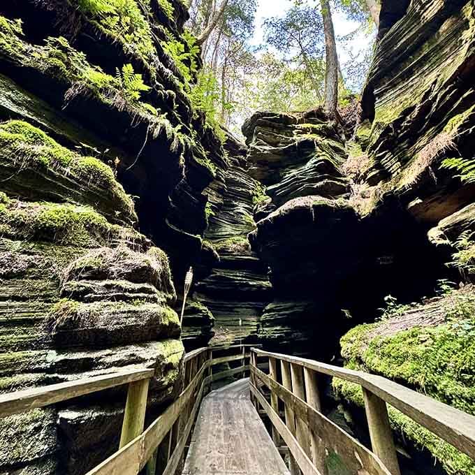 The wooden walkway leads deeper into shadows where rock walls seem to whisper secrets from ancient times.