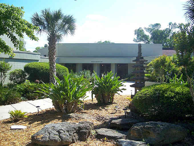 Tropical landscaping surrounds this mid-century building, creating a peaceful oasis in the heart of the community.