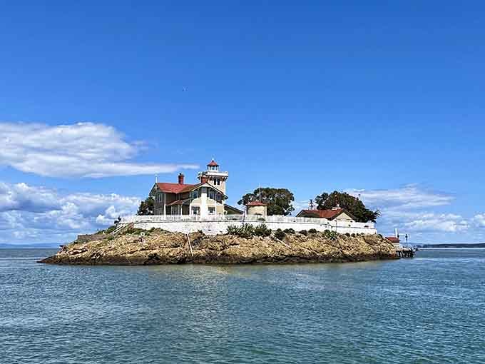 The calm bay waters surrounding this charming island station create a peaceful contrast to typical wild lighthouse locations nearby.