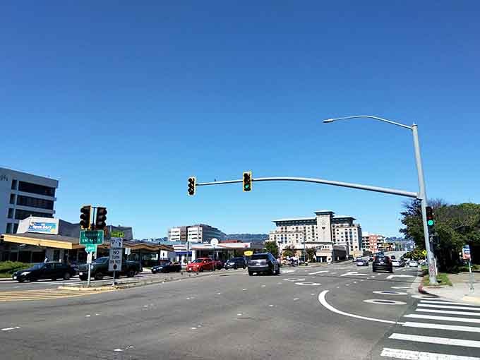 Traffic lights hang like patient conductors, orchestrating the daily rhythm of a town that moves at human speed.